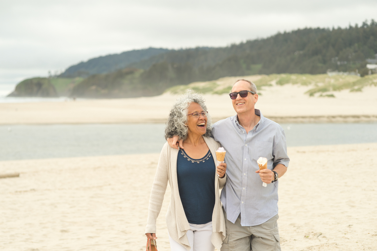 A senior couple eats ice cream cones as they walk along the beach | The ...